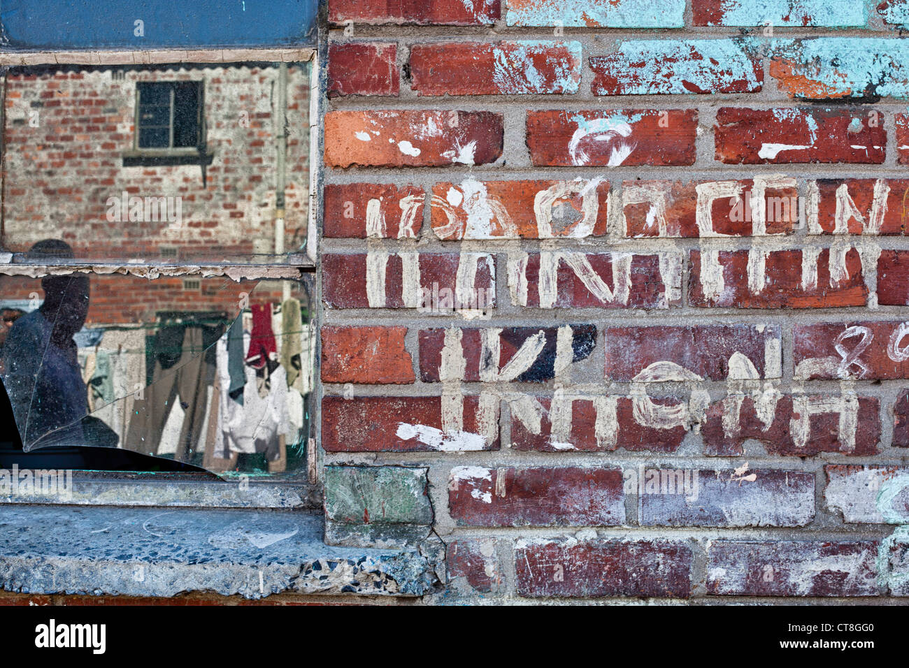 A reflection in a broken window and a brick wall advertising paraffin ...