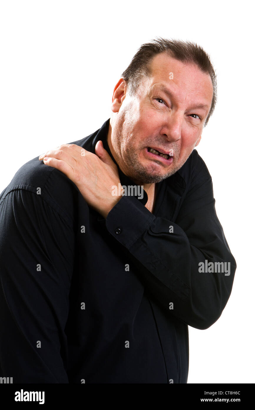 Elderly man suffering with a hurting shoulder rubs it with his hand and ...