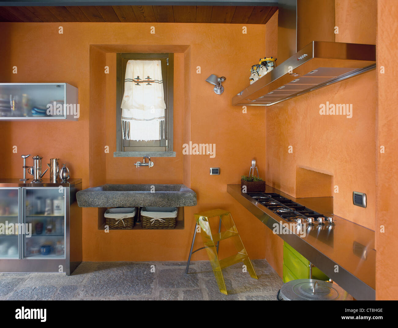 hi-tech kitchen with orange wall, stone sink and stone floor Stock ...