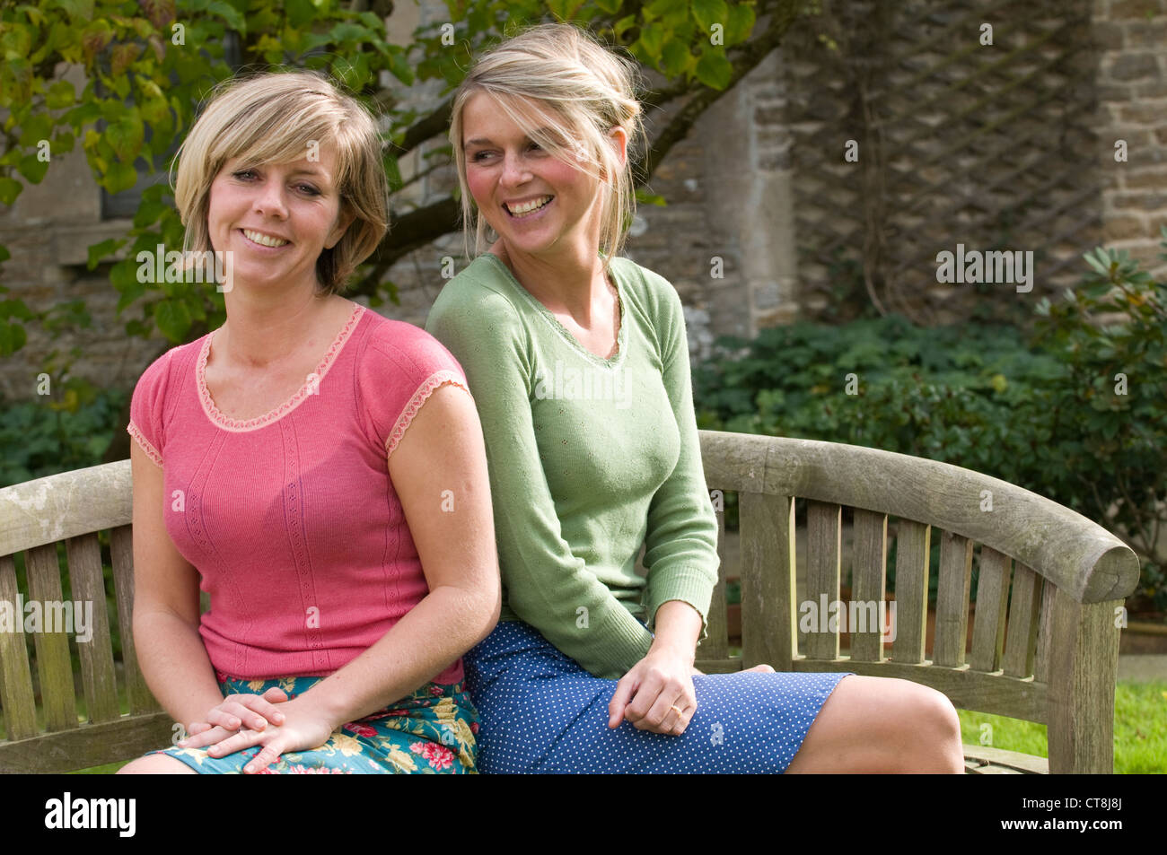 Two friends sitting on a garden bench together Stock Photo - Alamy
