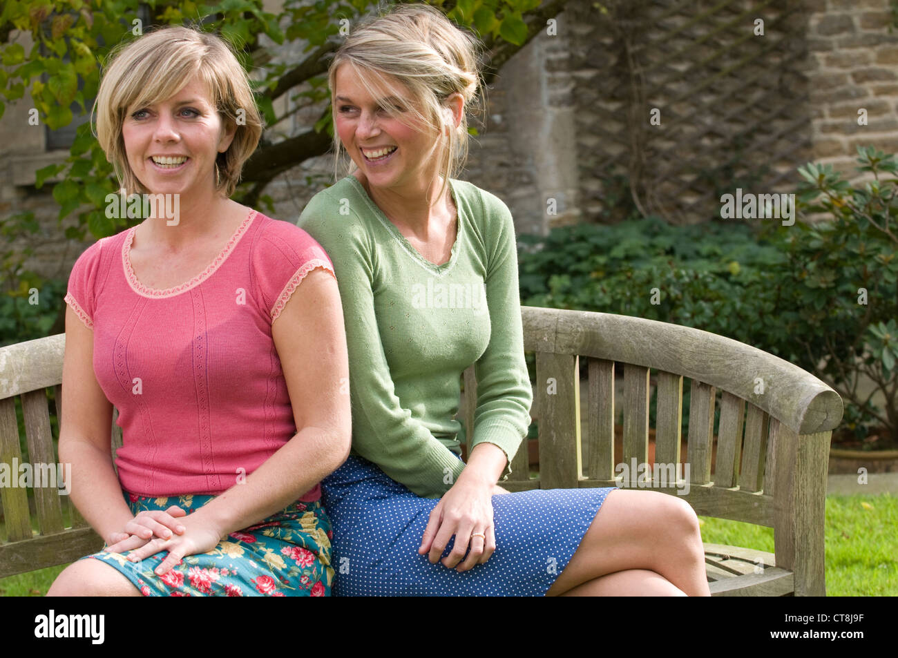 Two friends sitting on a garden bench together Stock Photo - Alamy