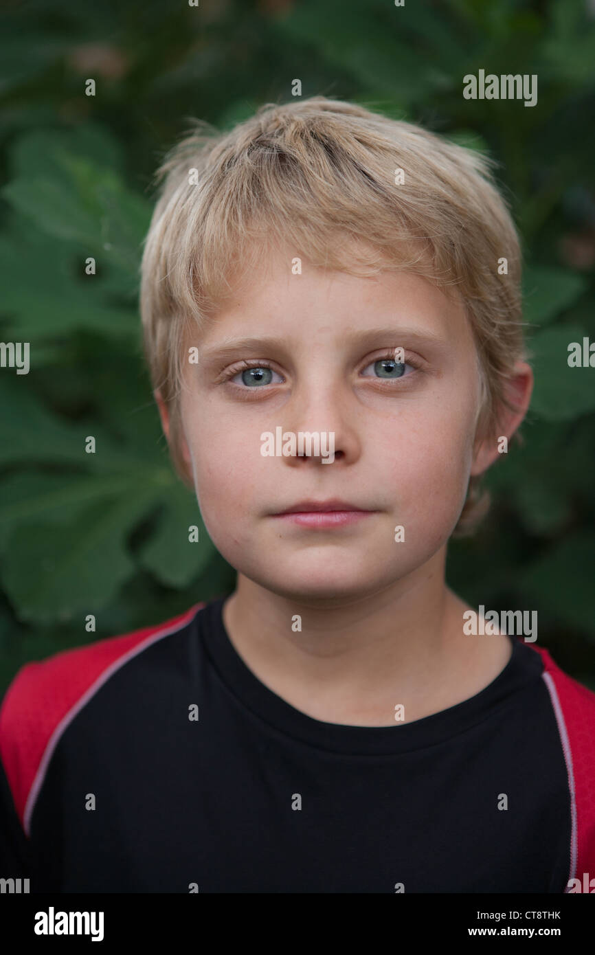 Ten year old boy with green eyes standing in front of a fig tree and ...