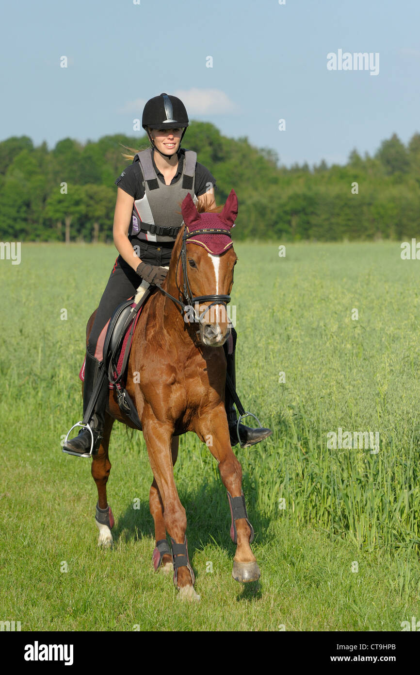 Young rider wearing a riding helmet and a body protector during a ride ...