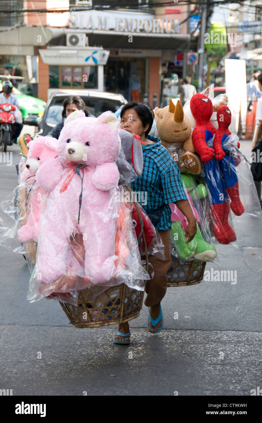 A stall holder carrying her toys hung from a long pole on her shoulder ...