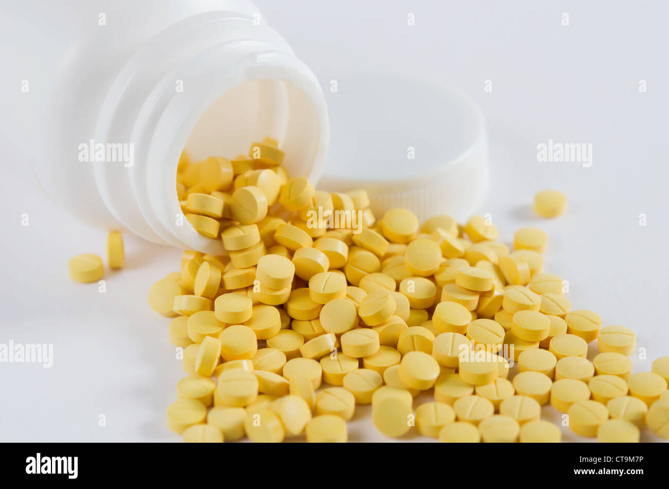 yellow medicine out of white bottle on white background Stock Photo - Alamy