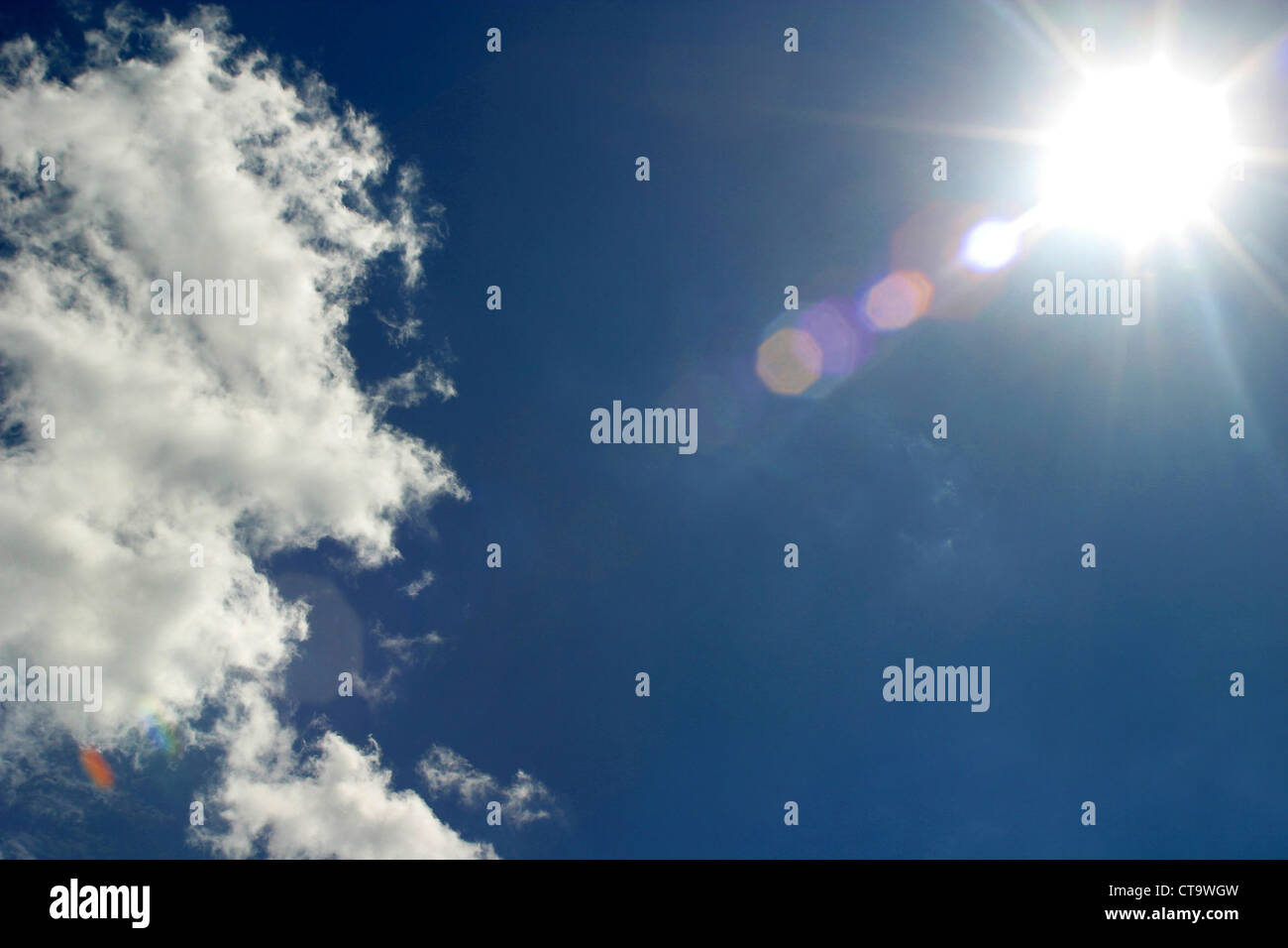 Dazzling sun against a blue sky with clouds Stock Photo - Alamy