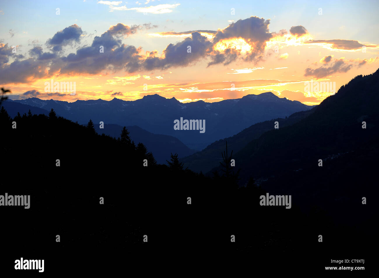 The sun sets behind a ridge of mountains in the Savoie region of the ...
