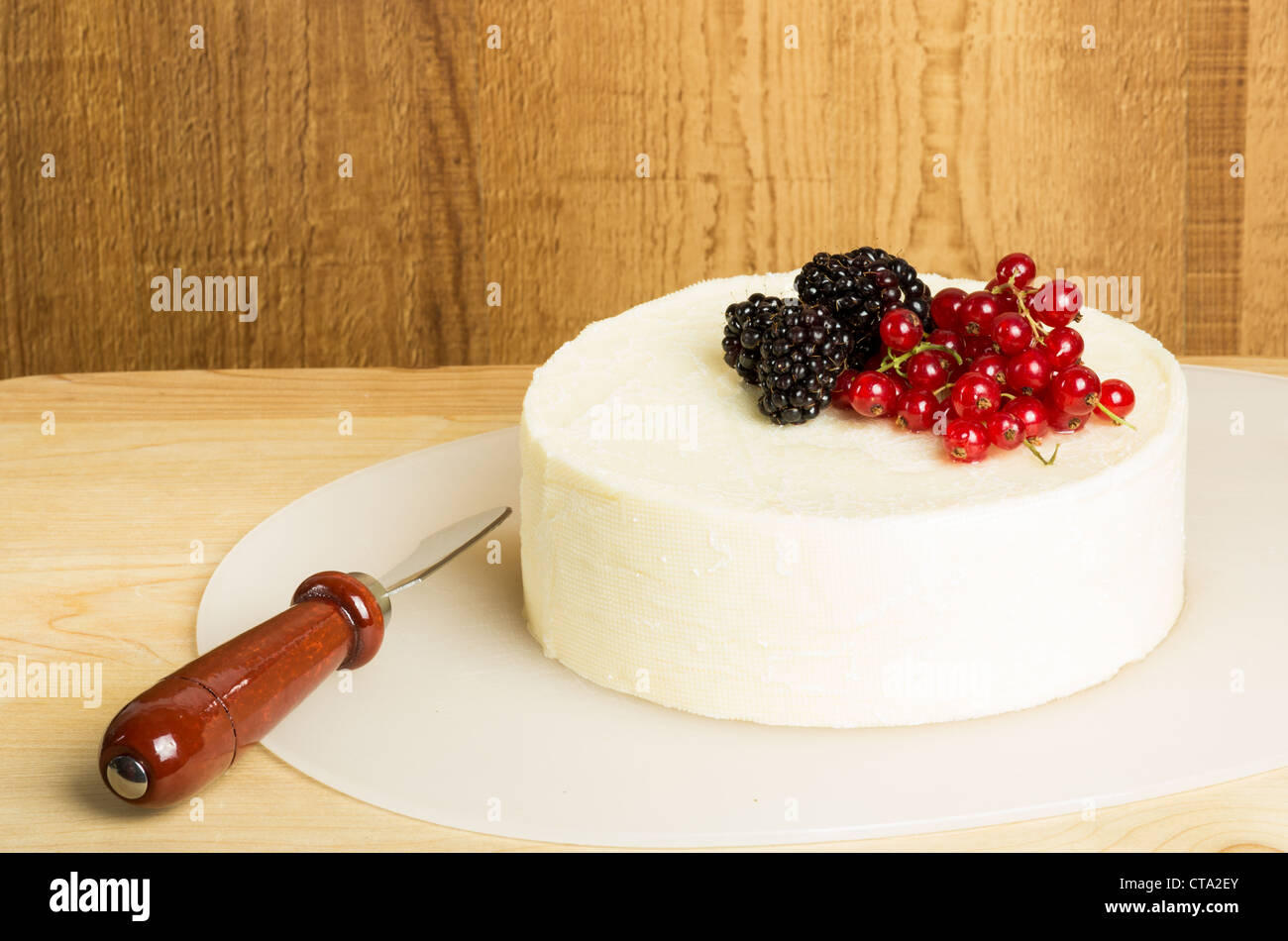 A round block of cheddar cheese topped with currants and blackberries ...
