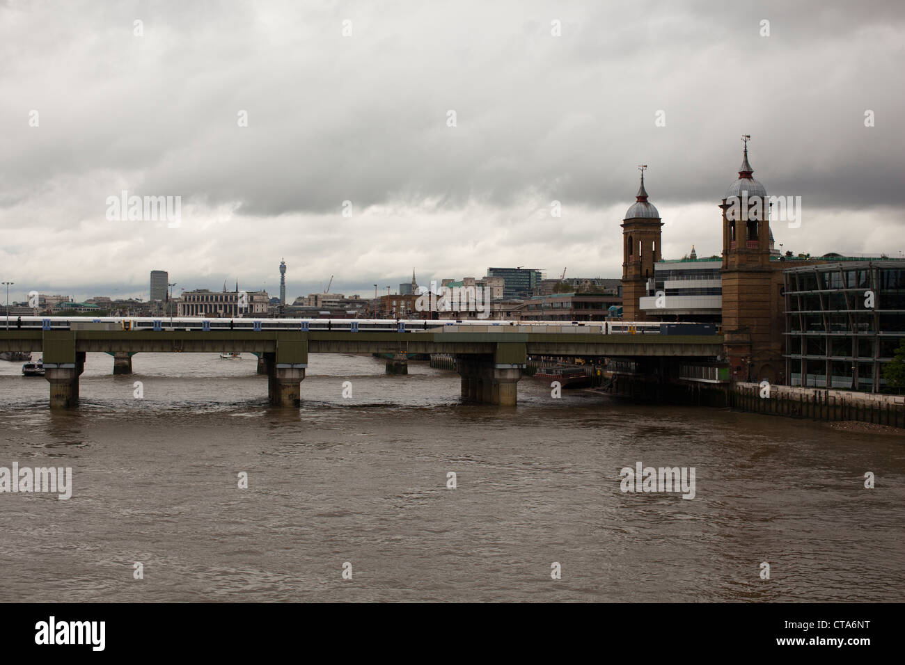 An Overground train travels across a Thames River bridge carrying rush ...