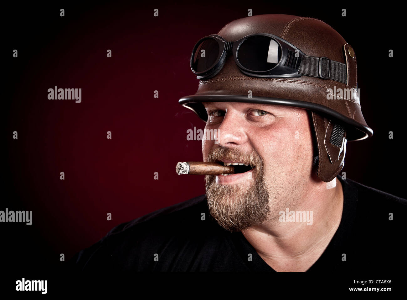 biker in a helmet smokes a cigar on a dark background Stock Photo - Alamy