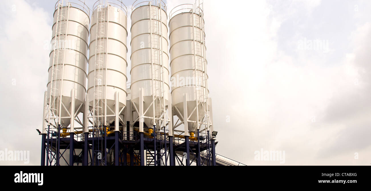 A conveyor belt connected to four white silos connected Stock Photo - Alamy