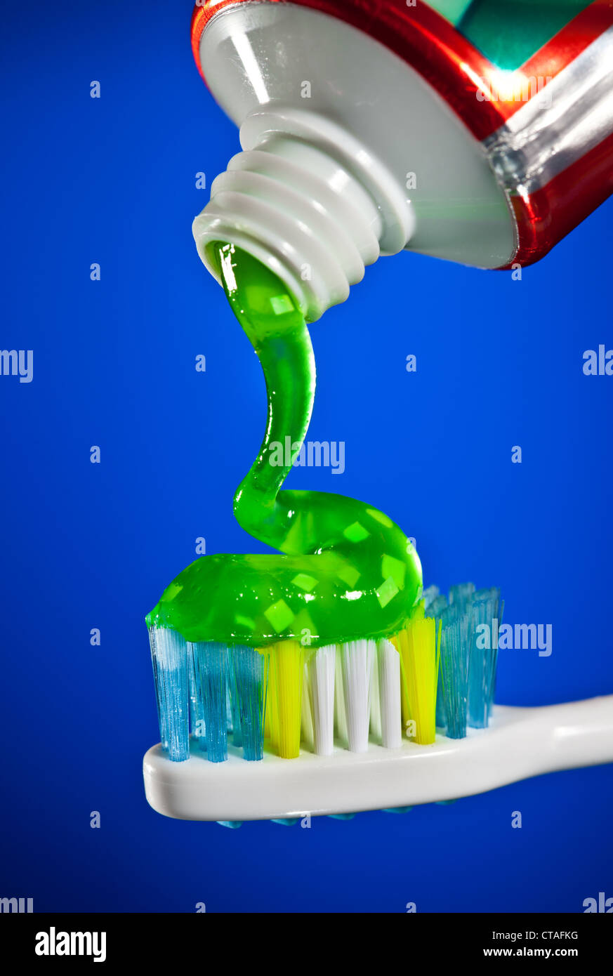 toothpaste being squeezed onto a toothbrush on a dark blue background ...