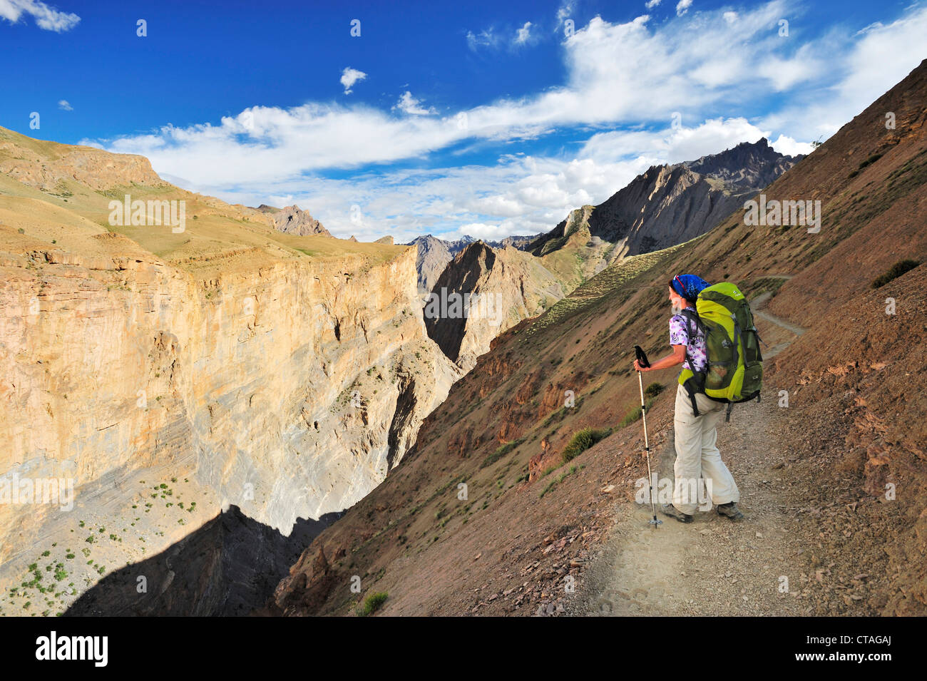 Woman with backpack looking over a gorge, Snertse, Zanskar Range ...