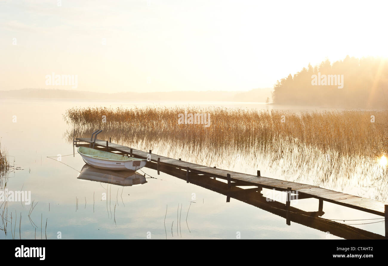 Rowing boat floating next to a jetty in a lake during sunset Stock ...