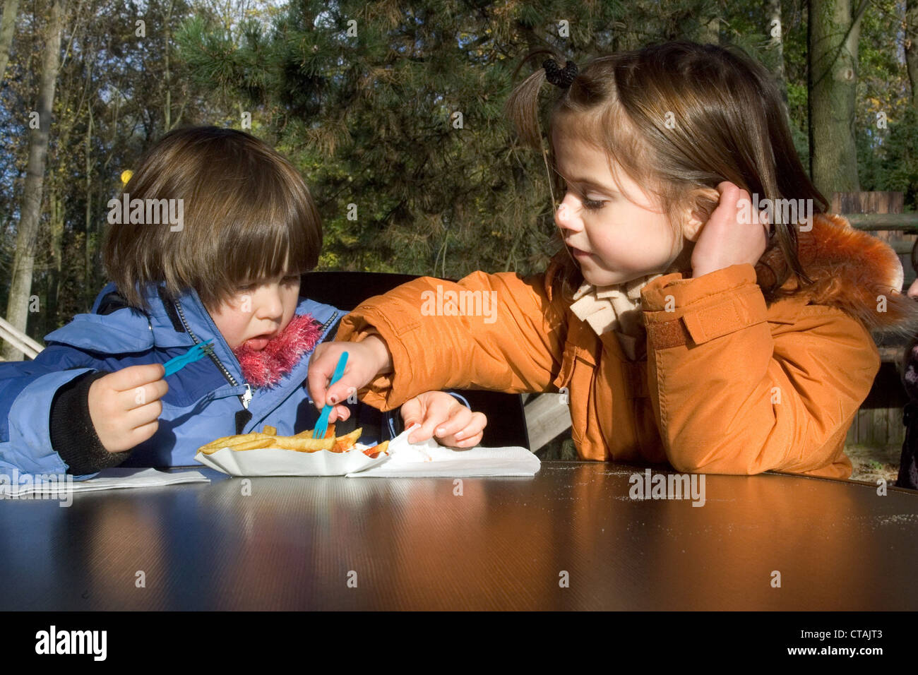 Two children eating French fries Stock Photo - Alamy