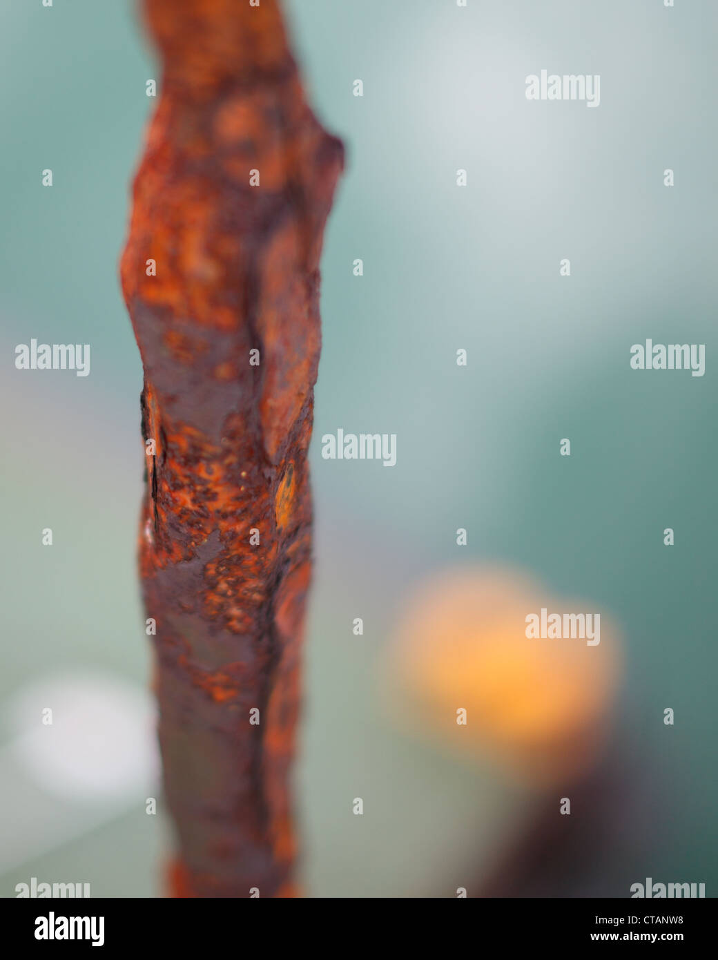 Rusty iron fence post against green background Stock Photo - Alamy