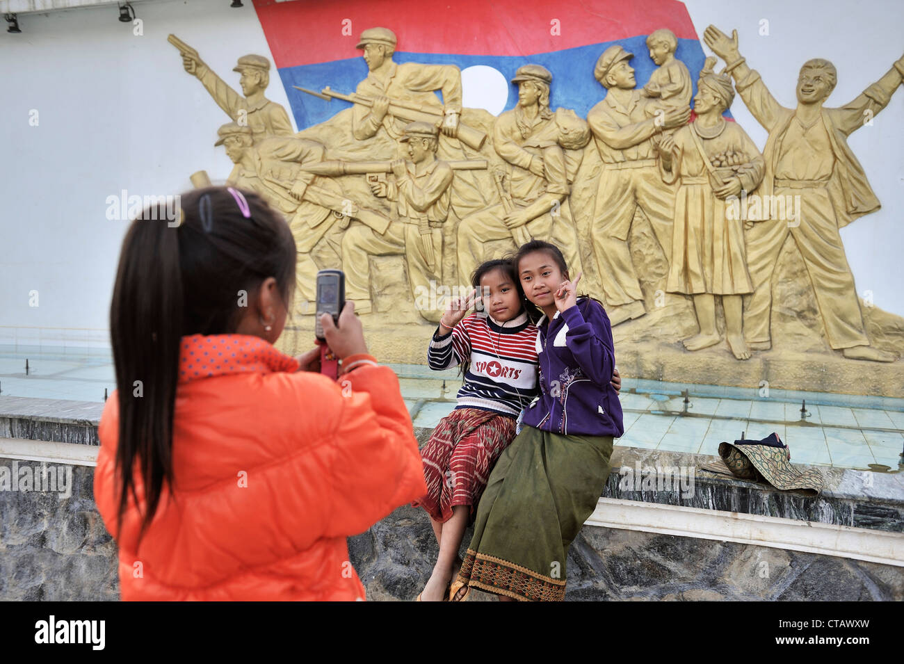 Young people of Laos posing for photo in front of a communist monument ...
