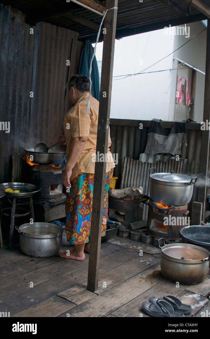A Thai woman cooking in a wooden shack at a food market in Bangkok ...