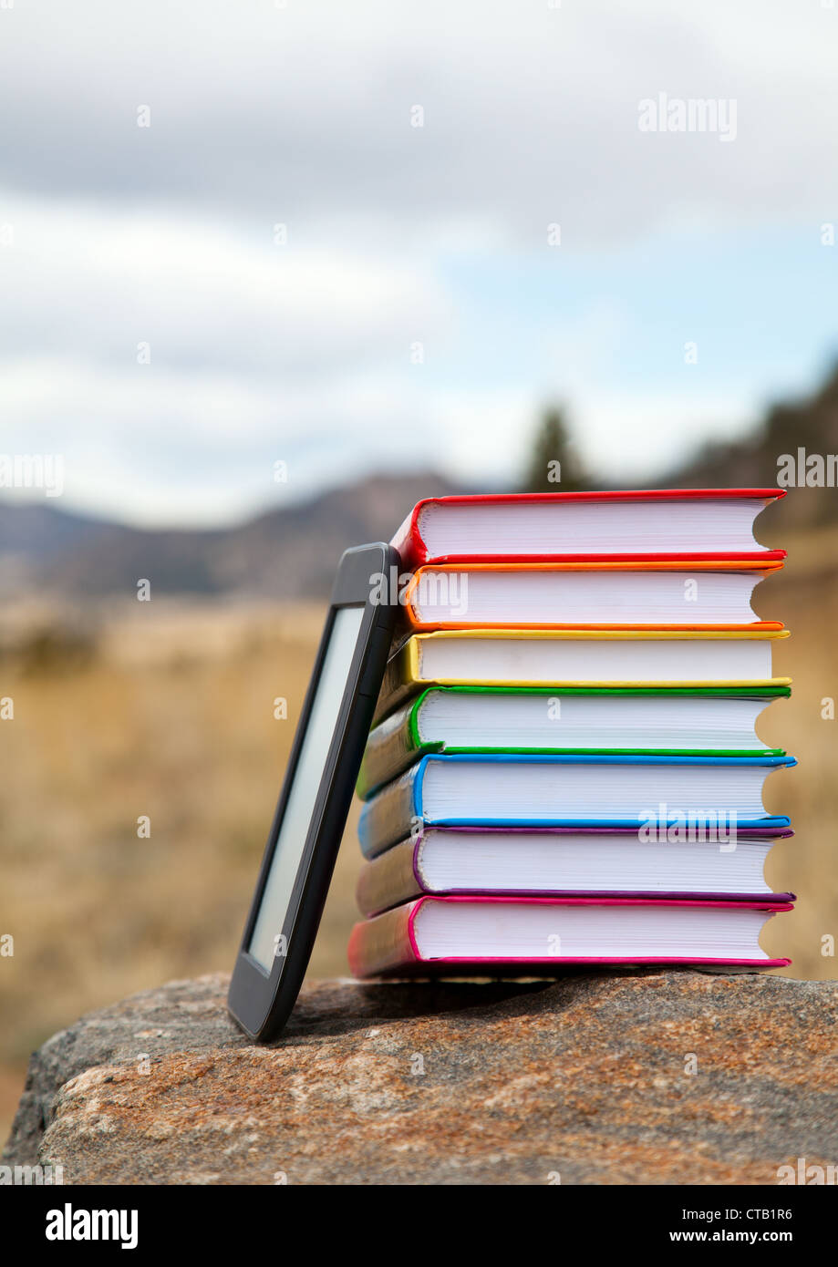 Stack of printed books with electronic book reader lying on the stone ...
