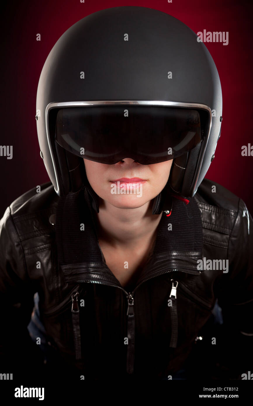 Biker girl in a helmet on a red background Stock Photo - Alamy