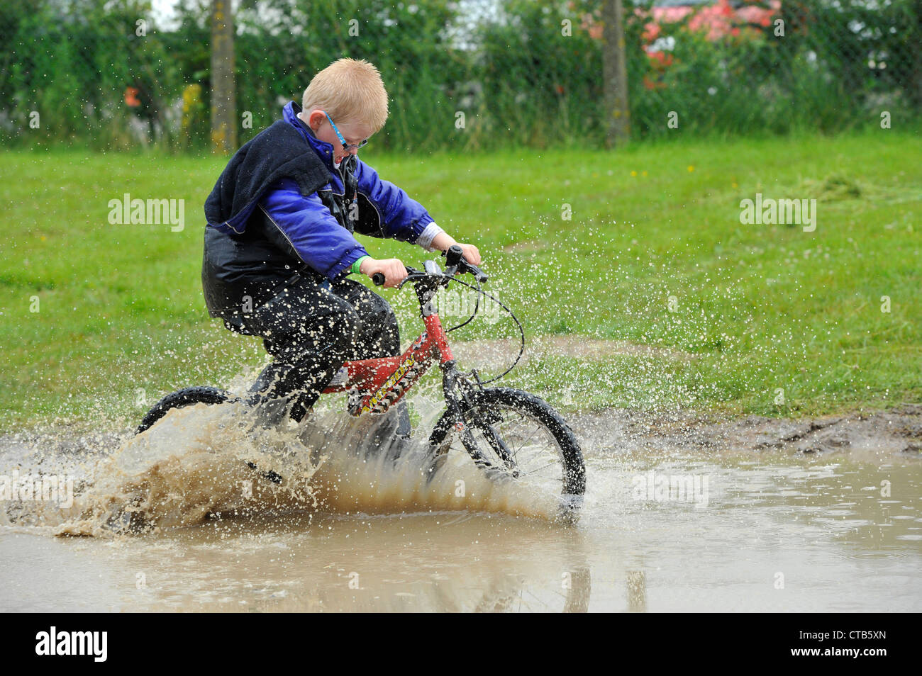 Child on a bike racing through a puddle creating a splash Stock Photo ...