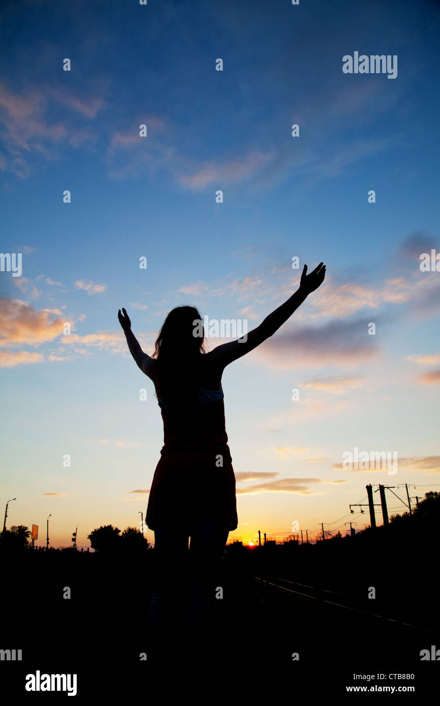 Woman staying with raised hands at the sunset time Stock Photo - Alamy