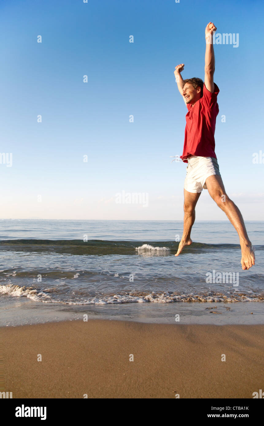 Young man takes a great leap on a beach at sunrise: happiness, fitness ...