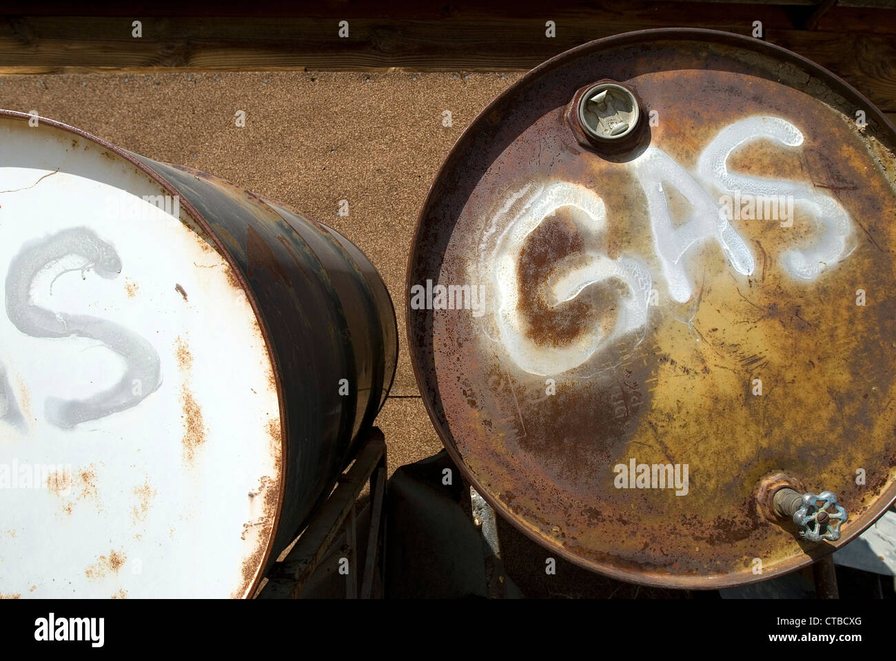 two abandoned gas cans in a junkyard spray painted with the word "gas ...