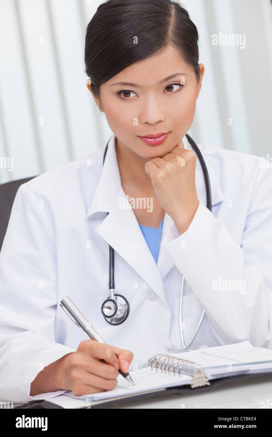 A Chinese Asian female medical doctor writing in a hospital office ...