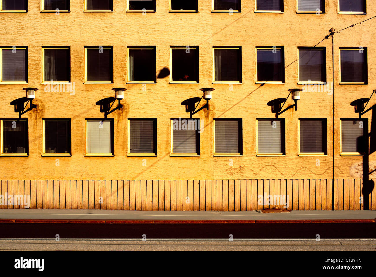 Lights casting strong shadows on a bright yellow building with many ...