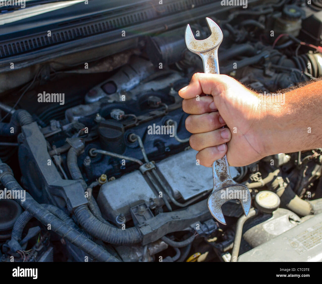 Hand holding spanner against car engine Stock Photo - Alamy