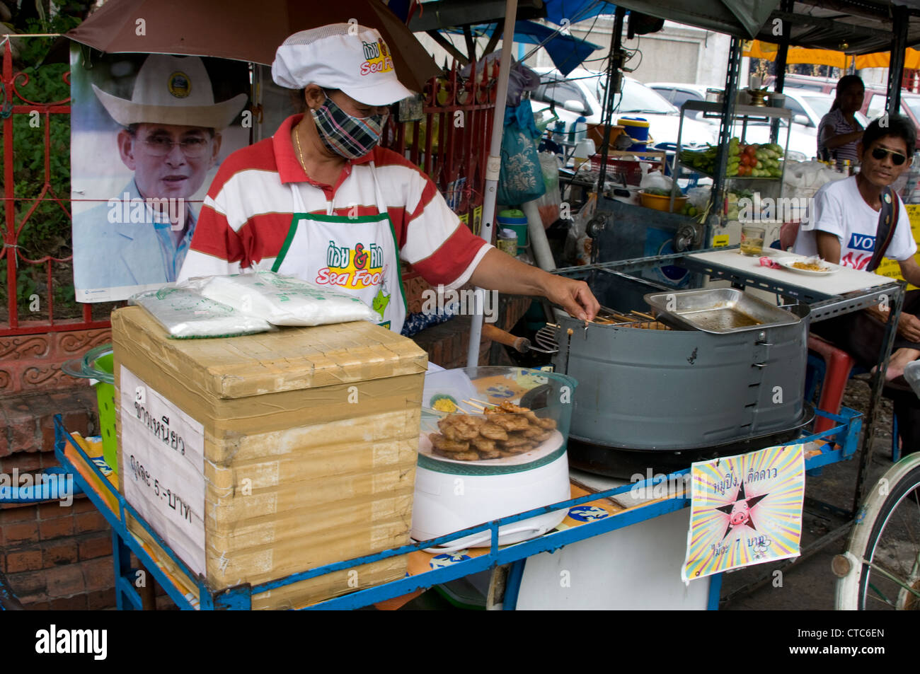 A food vendor wearing his face mast preparing Thai food on his food ...