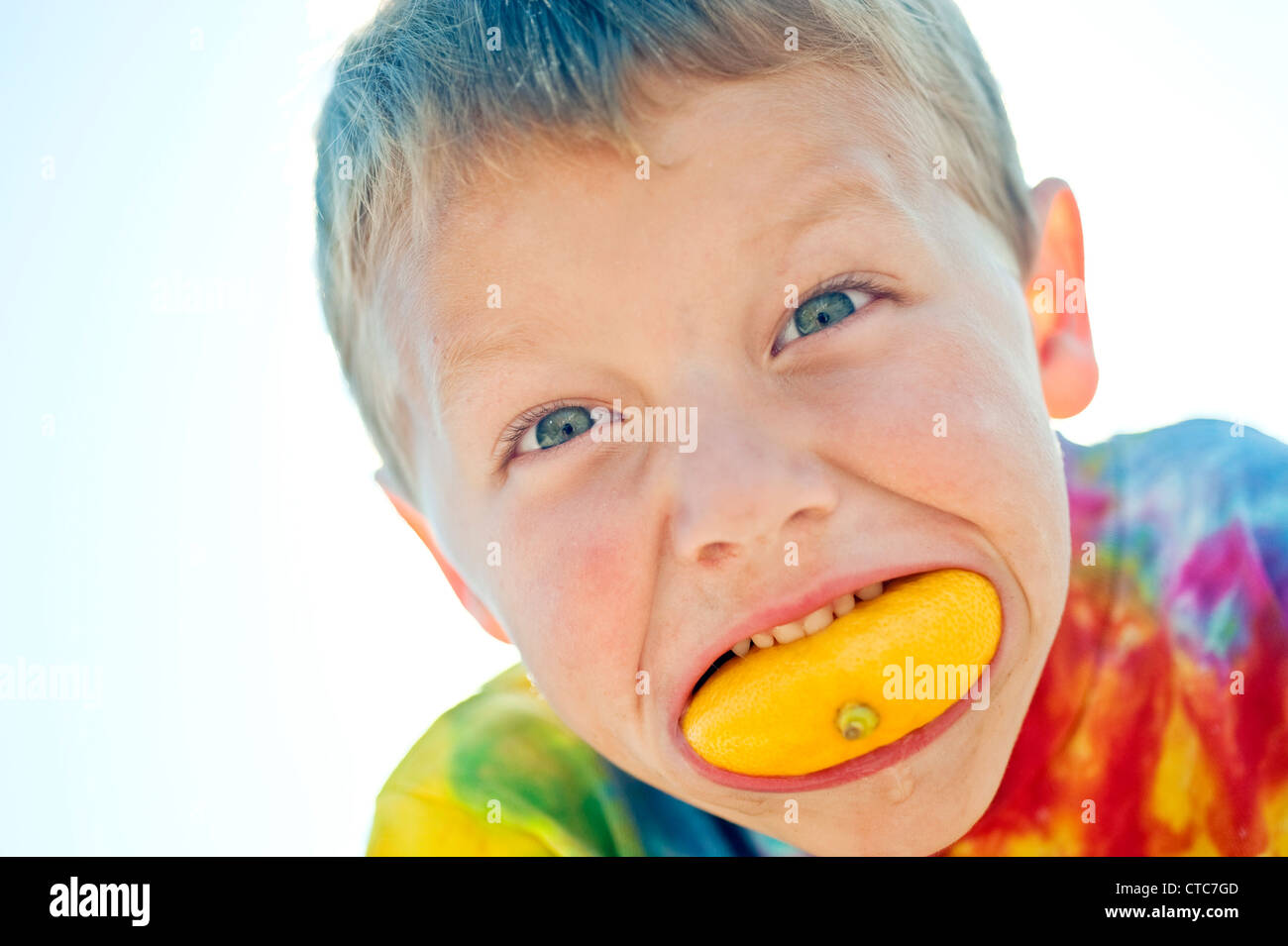 A boy smiles with a lemon in his mouth Stock Photo - Alamy