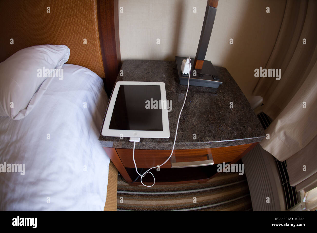 Ipad plugged into an outlet at the base of a lamp, charging Stock Photo ...