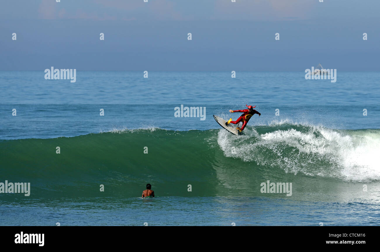 Bearded man surfing a wave wearing red superhero costume Stock Photo ...