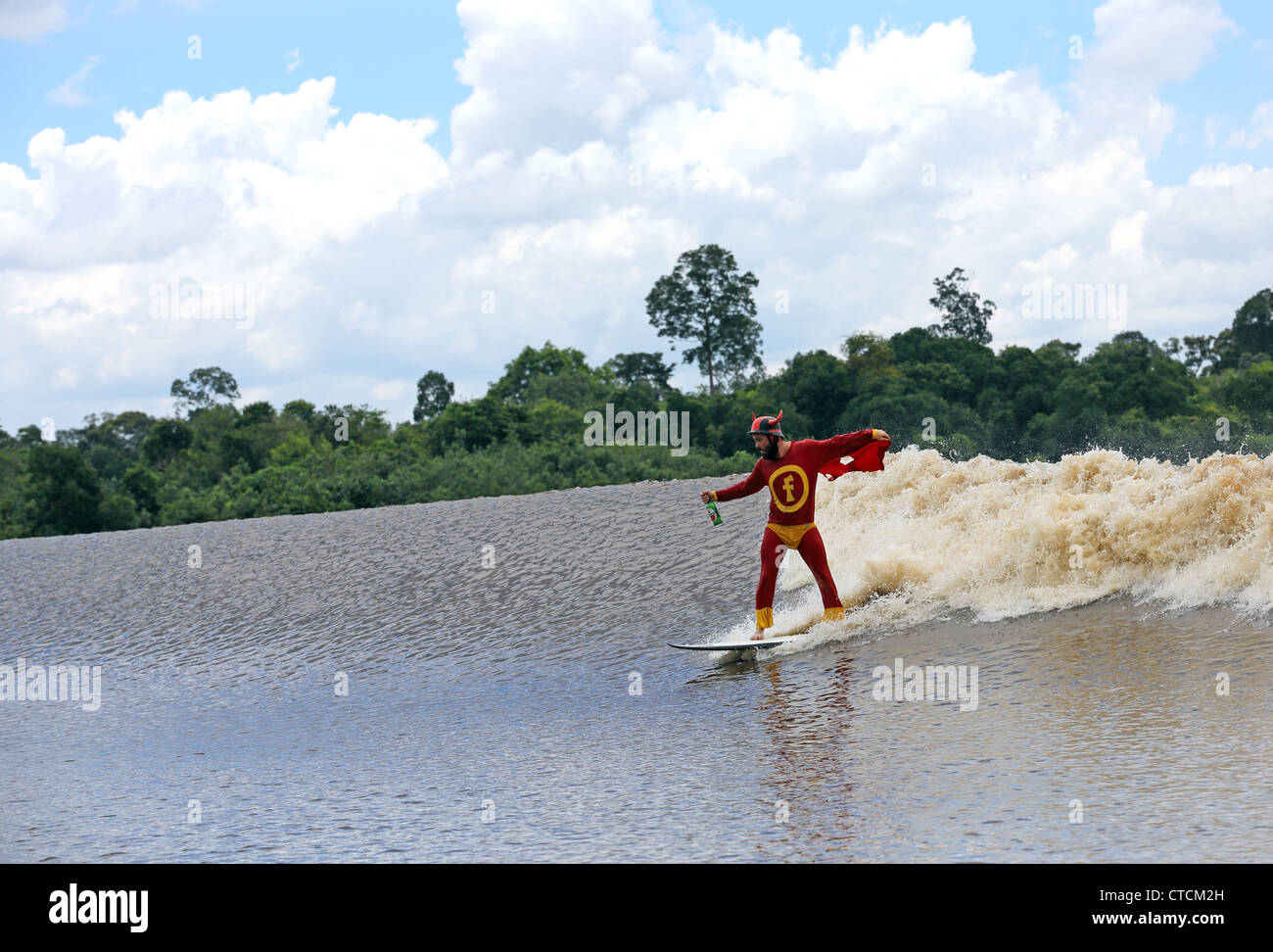 Strange man in red superhero costume river surfing a tidal bore wave on ...