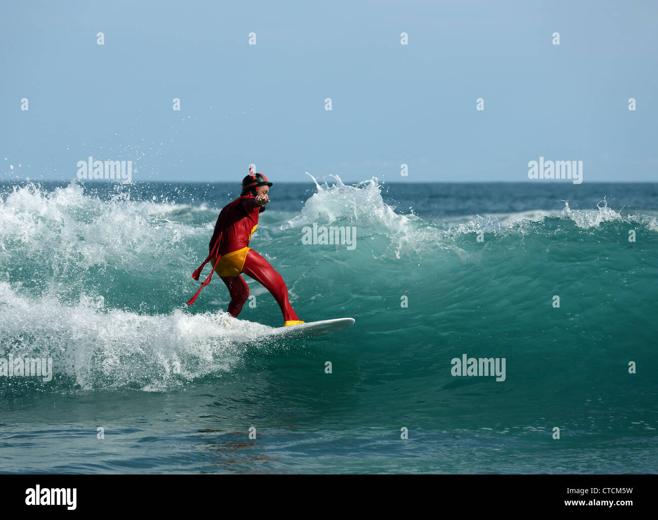 Bearded man surfing a wave wearing red superhero costume Stock Photo ...