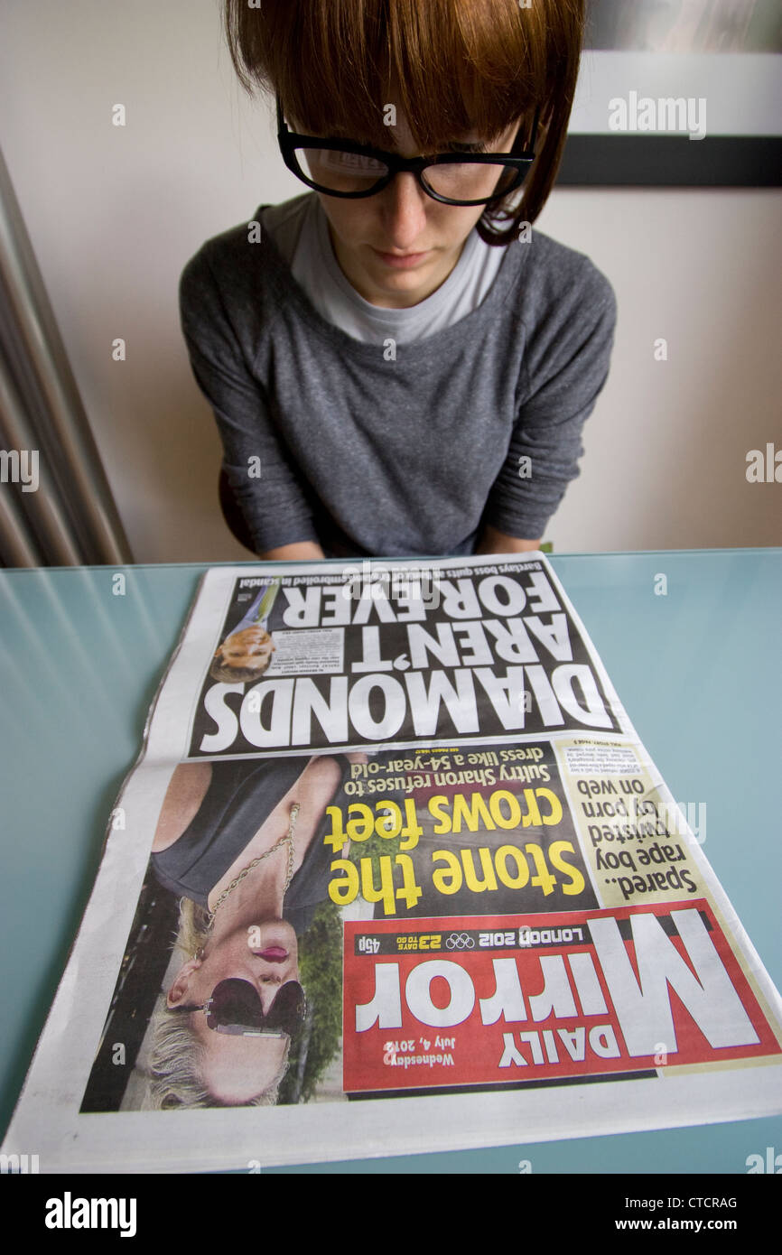 A young female reads the UK edition of the Daily Mirror newspaper at a ...