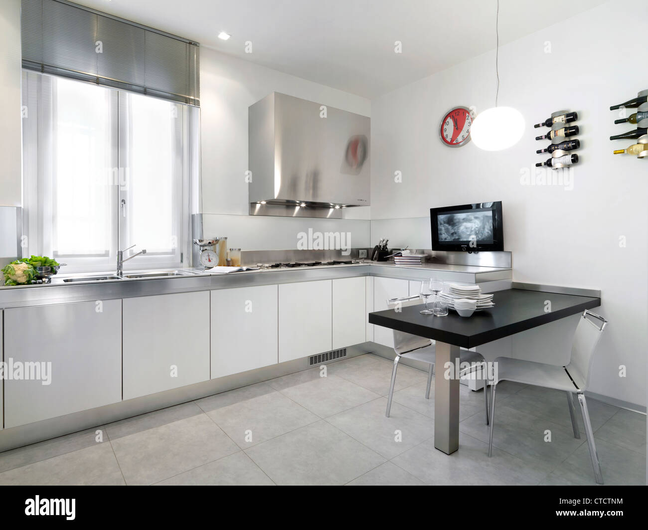 modern white kitchen with dining table and dishes on it Stock Photo - Alamy