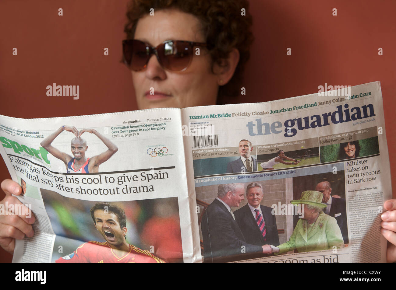 Woman reading a copy of the Guardian newspaper Stock Photo - Alamy