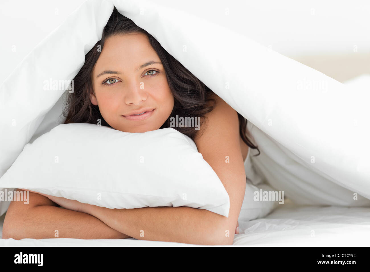 Smiling woman hugging a pillow Stock Photo - Alamy