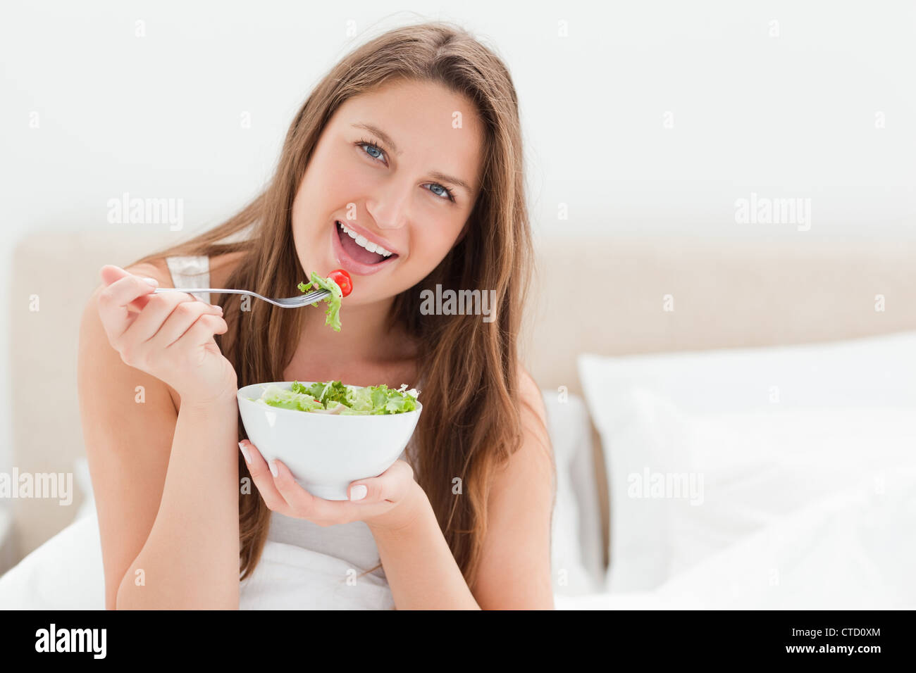 Cute woman smiling while eating a salad Stock Photo - Alamy