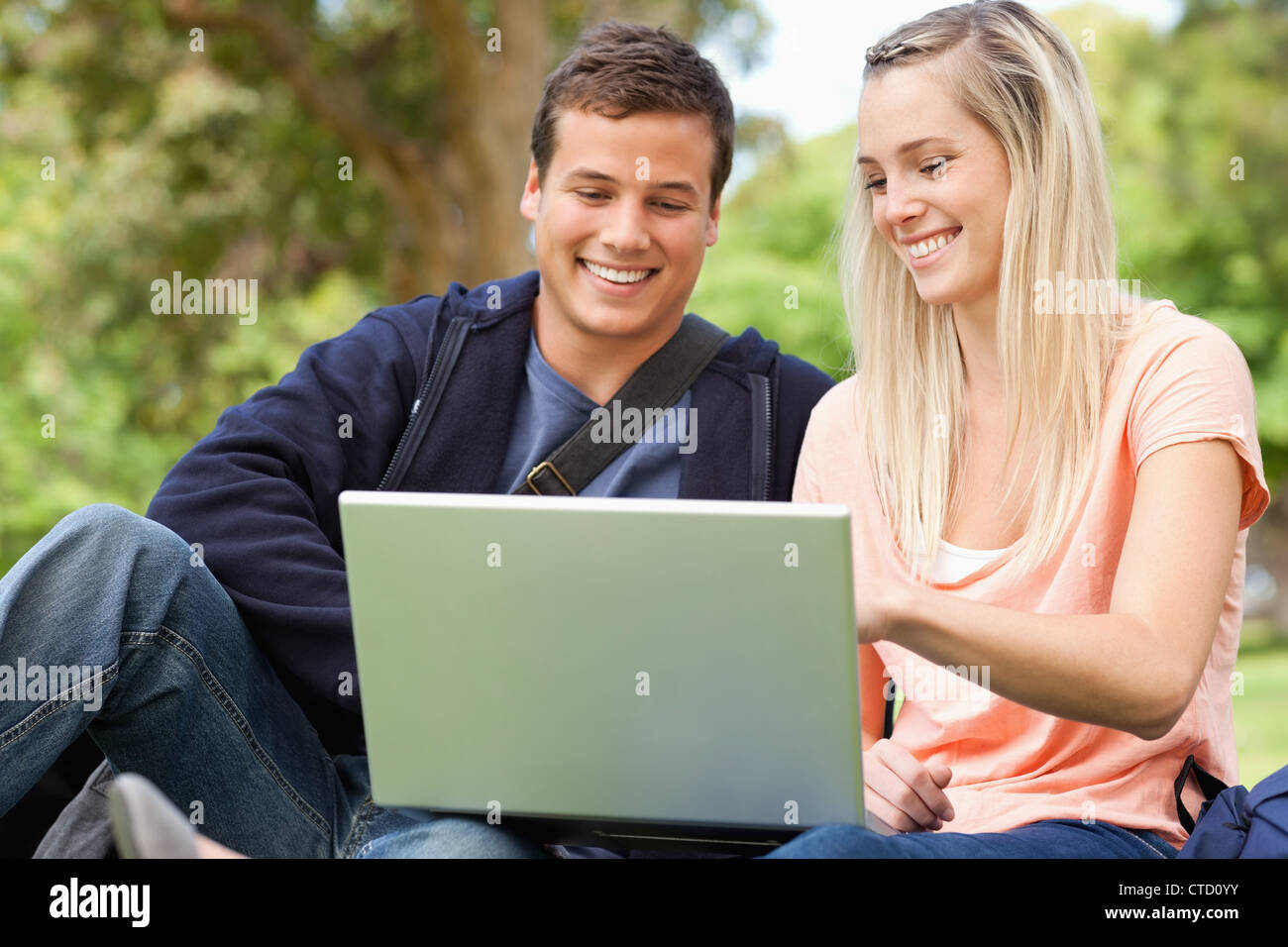 Young people sitting while using a laptop Stock Photo - Alamy