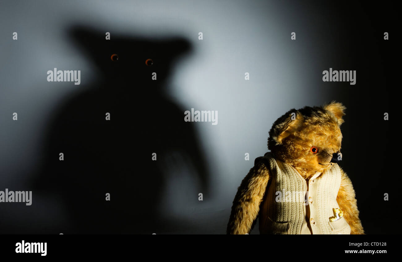 A lone Teddy Bear standing with it's shadow on the wall behind it there ...