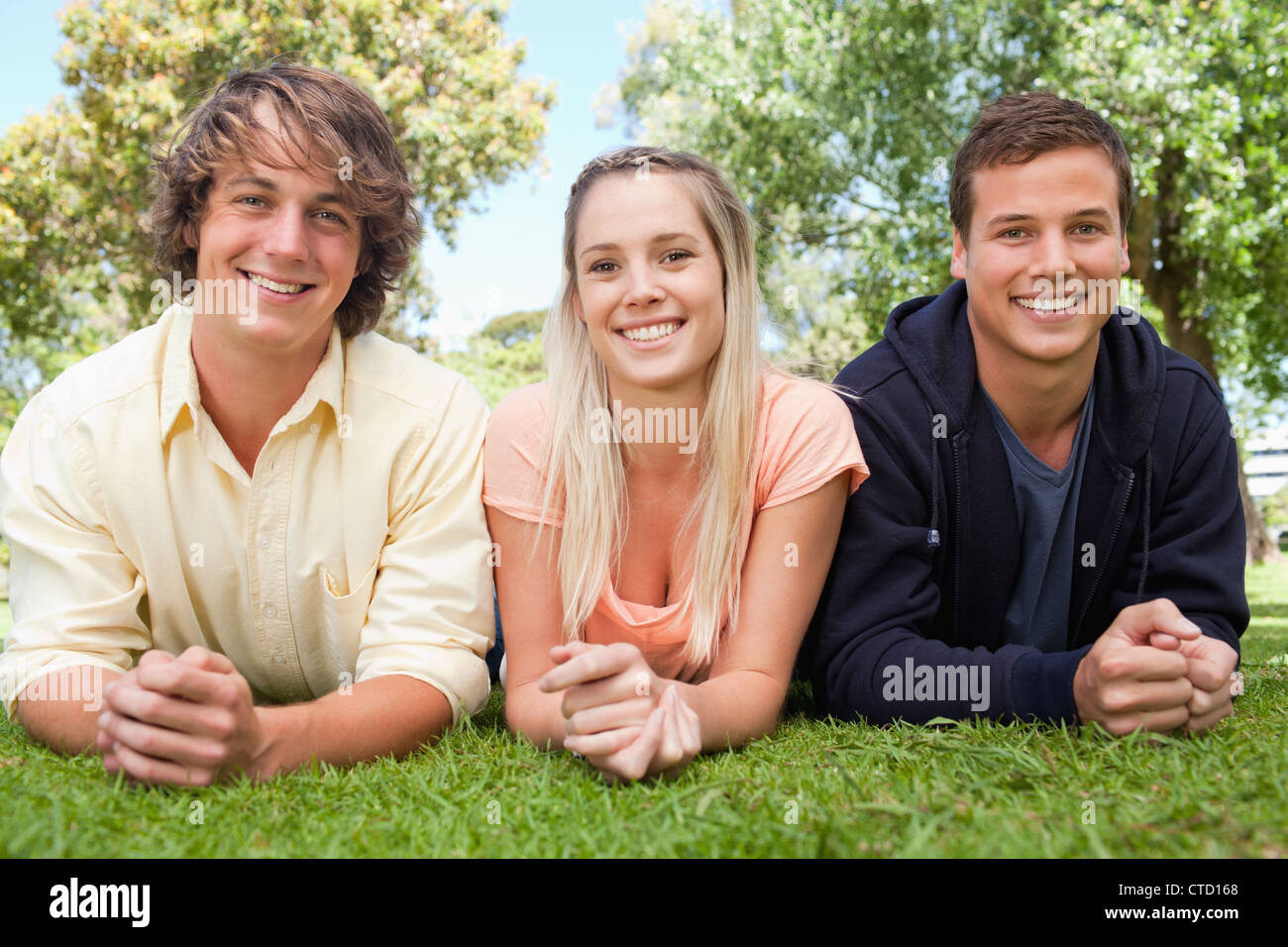 Portrait of three smiling students in a park Stock Photo - Alamy