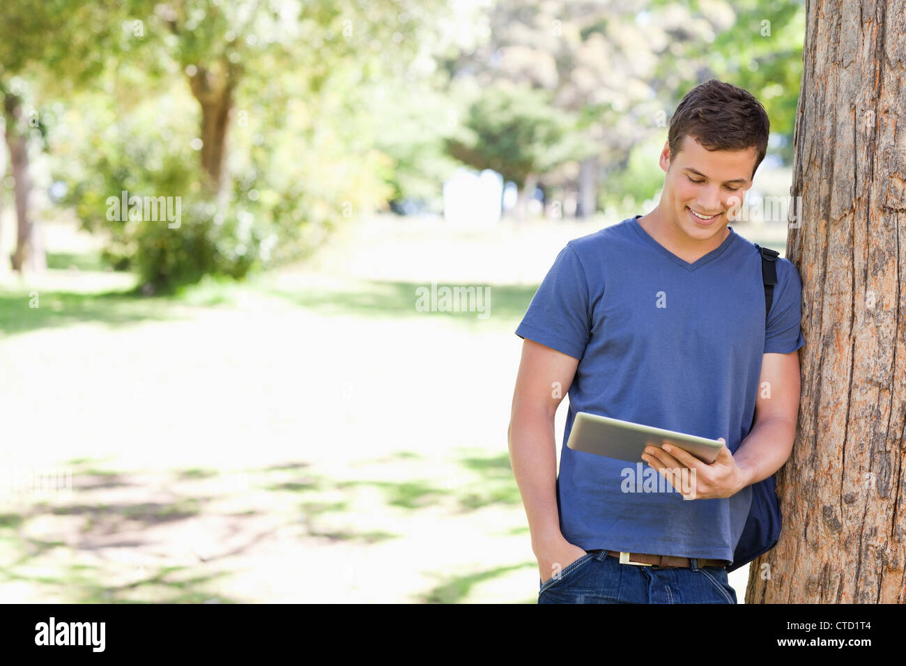 Student leaning against a tree Stock Photo - Alamy