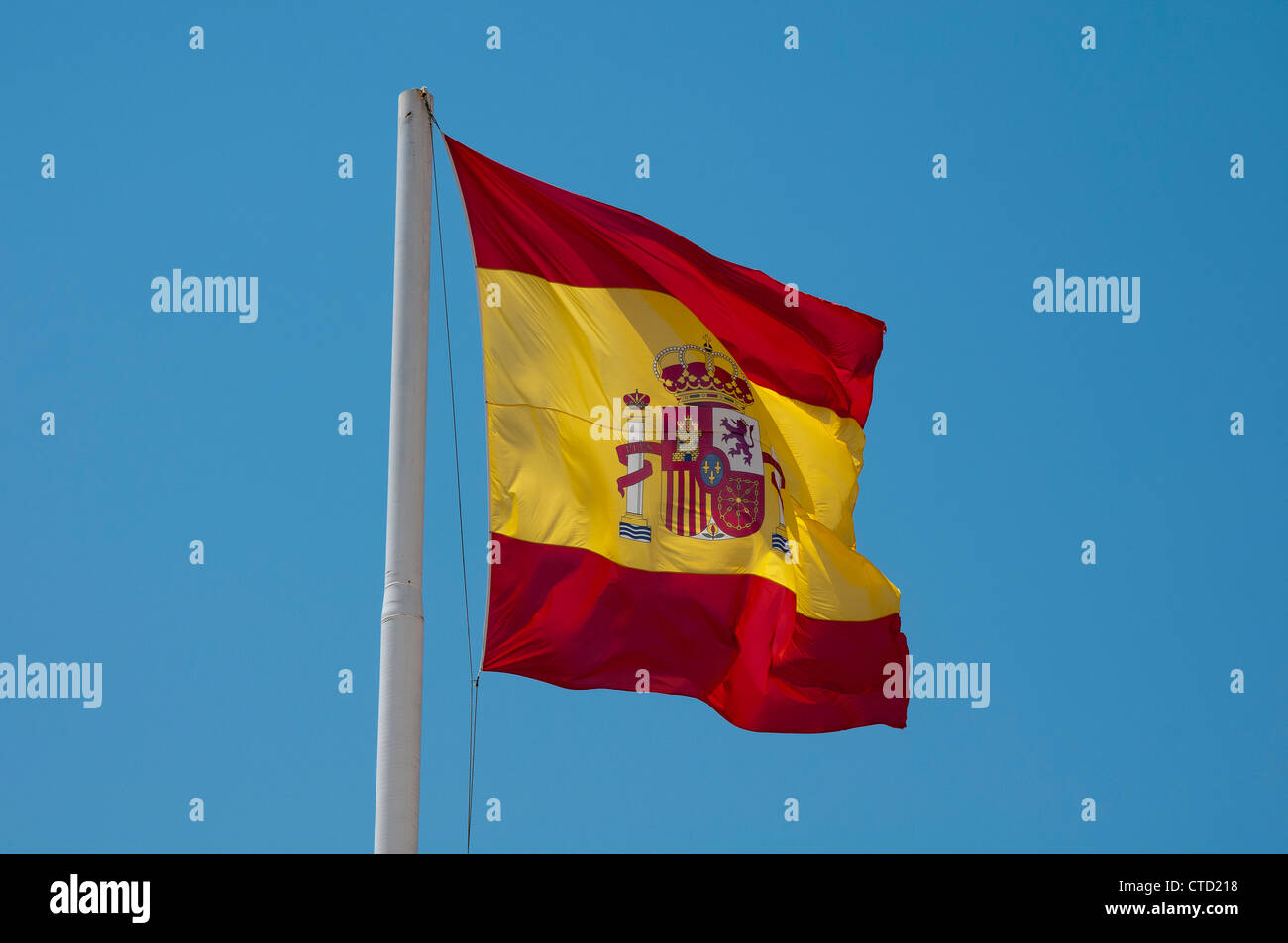 Spanish national flag flying from a pole with a blue sky background ...