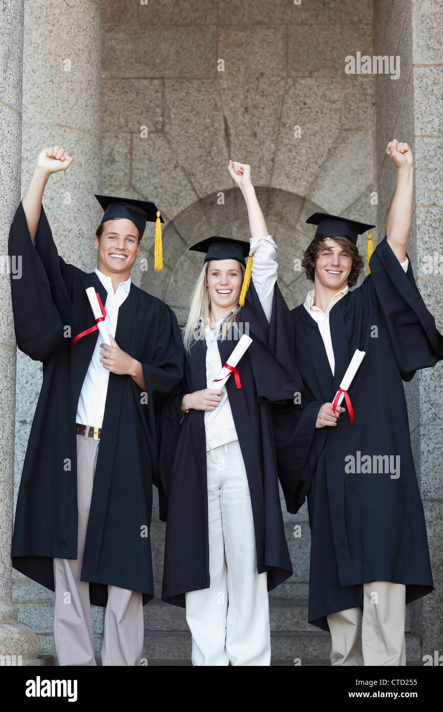 Happy graduates raising arm Stock Photo - Alamy