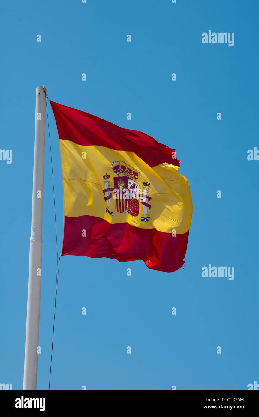 Spanish national flag flying from a pole with a blue sky background ...