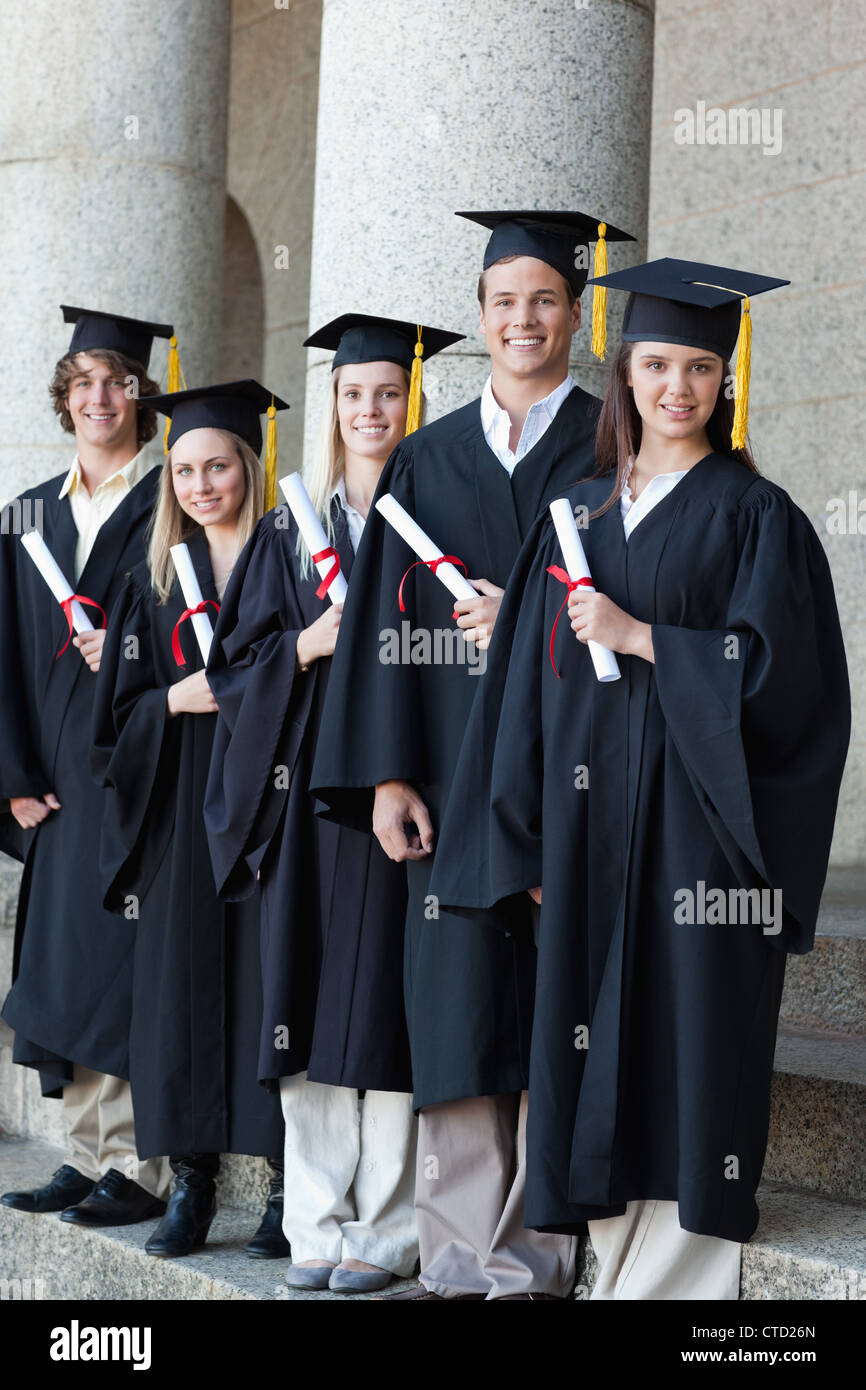 Happy graduates posing in single line Stock Photo - Alamy
